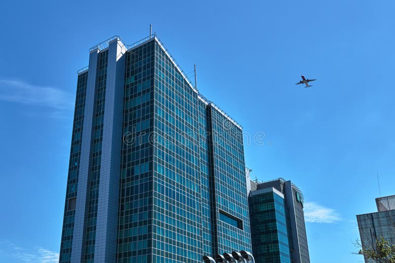 A Plane Flying Over Modern Office Buildings Stock Image - Image of ...