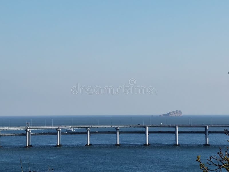 An Airplane is Flying Low Over the Water and Bridge at the End of a ...