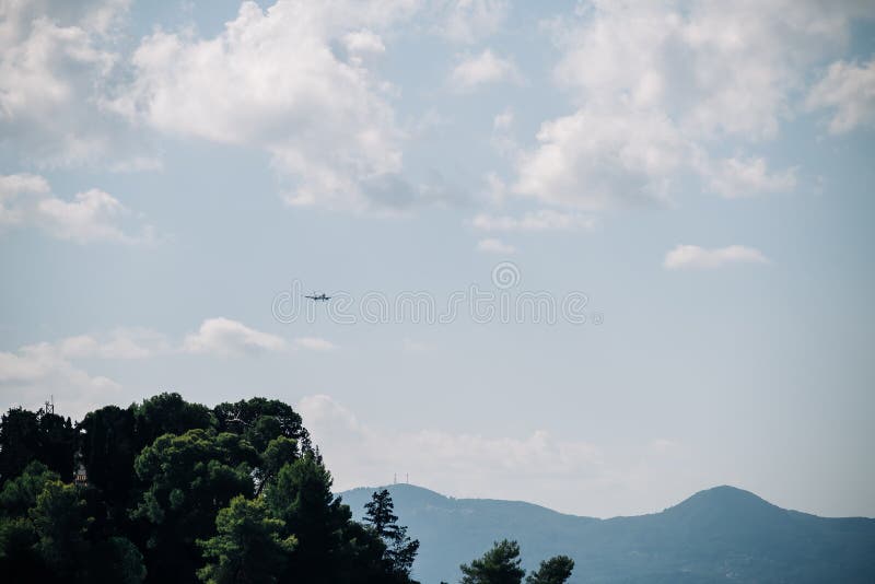 Plane Soars Over Trees, Mountains with Clouds in Sky Stock Photo ...