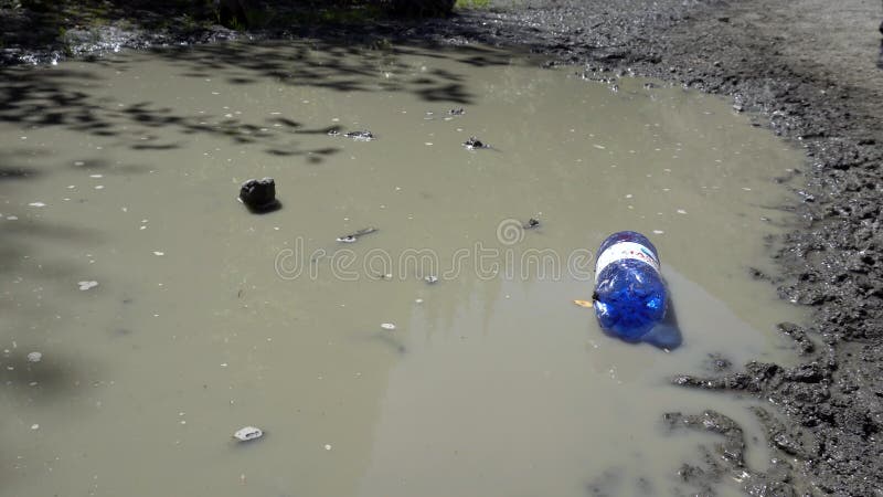 A Plastic Bottle is Lying in a Muddy Puddle. Stock Footage - Video of ...