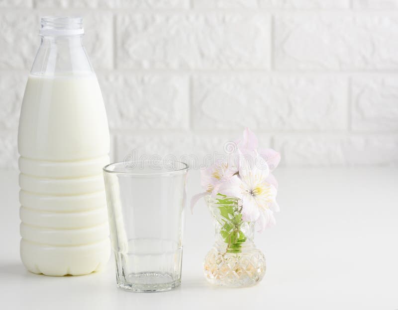 Plastic Bottle with Milk and Empty Glass Cup on a White Table ...