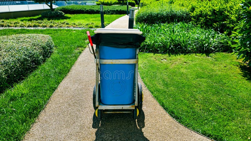 A Plastic Garbage Container and Cleaning Supplies Stand in the Yard ...