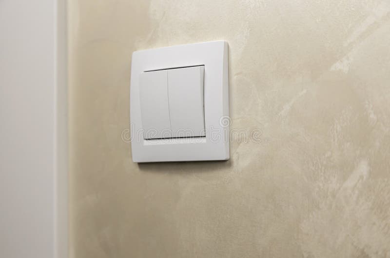 A Plastic Mechanical Switch of White Color on a Light Wall. Turn the ...