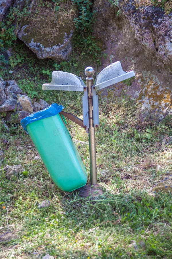 A Plastic Trash Bin Standing in the Ground. a Metal Post Holding the ...