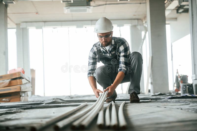 Plastic Tubes in Hands. Construction Worker in Uniform in Empty ...