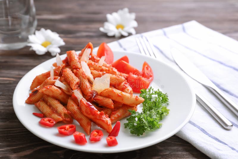 Plate with Delicious Penne Pasta and Garnish on Table Stock Photo ...