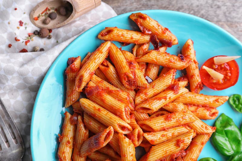 Plate with Delicious Penne Pasta and Garnish on Table Stock Photo ...