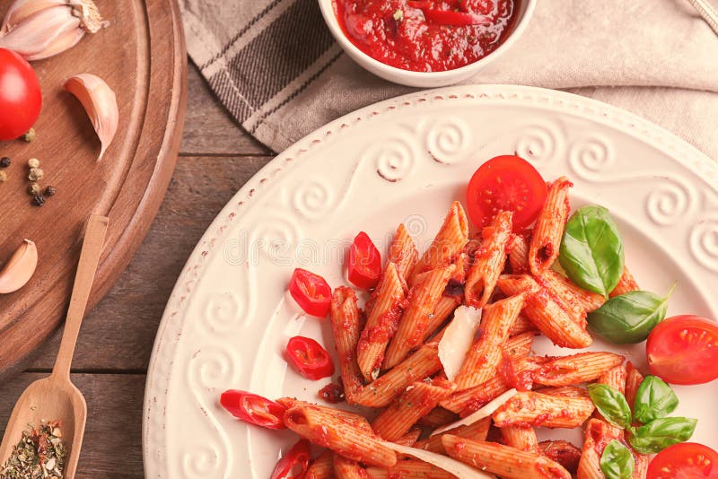Plate with Delicious Penne Pasta and Garnish on Table Stock Photo ...