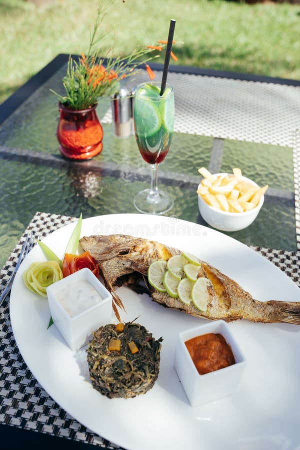 Plate of Fried Fish Decorated with Lemons and Vegetables on Restaurant ...