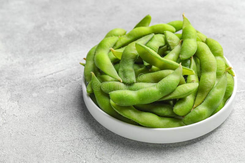Plate with Green Edamame Beans in Pods on Light Grey Table. Space for ...