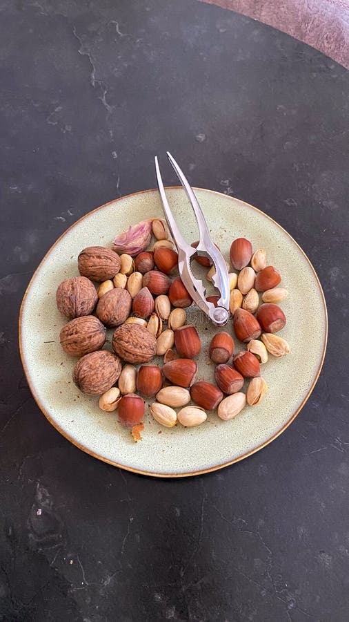 A Plate of Nuts on a Table with a Pair of Tongs Stock Photo - Image of ...