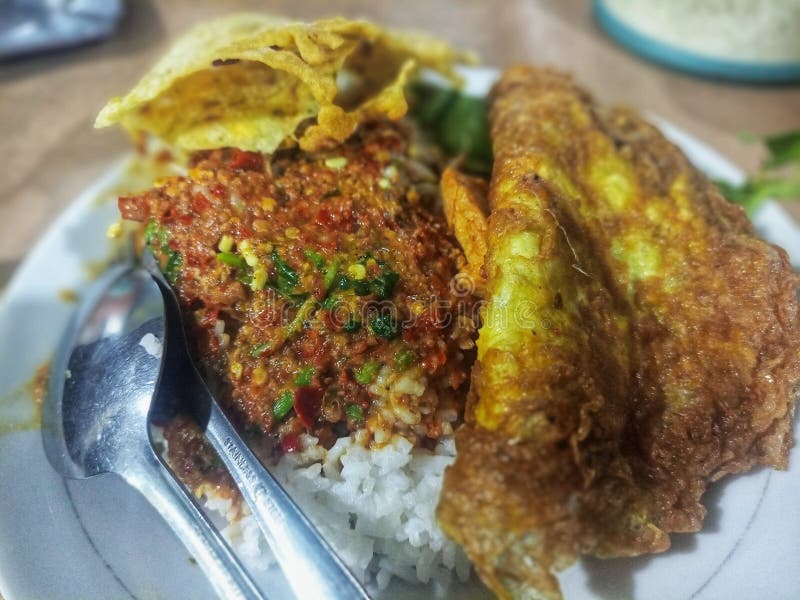 A Plate of Pecel Rice with Peanut Sauce Topped with Peyek and Fried Egg ...