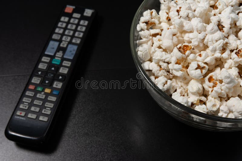 A Plate of Popcorn and a TV Remote on a Black Background. Stock Image ...