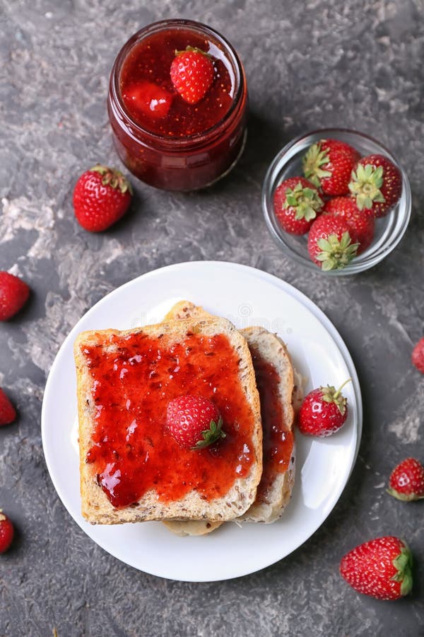 Plate with Slices of Bread and Delicious Strawberry Jam on Grunge Table ...
