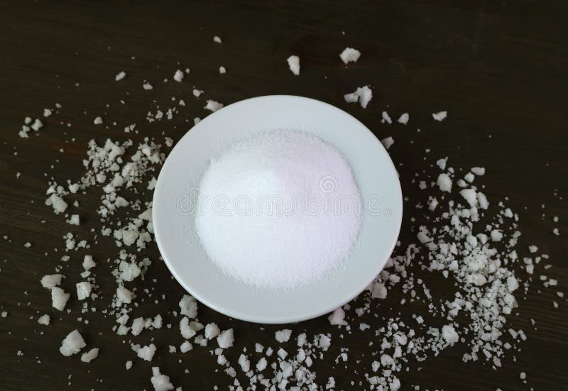 Plate of Table Salt on Black Wooden Table with Sea Salt Scattered ...