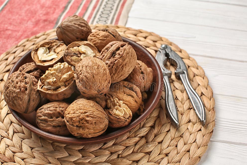 Plate with Tasty Walnuts and Nutcracker on Wicker Mat Stock Image ...