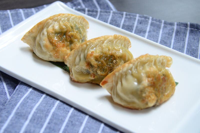 Three Dumplings and Vegetables on this Plate on the Table Stock Image ...