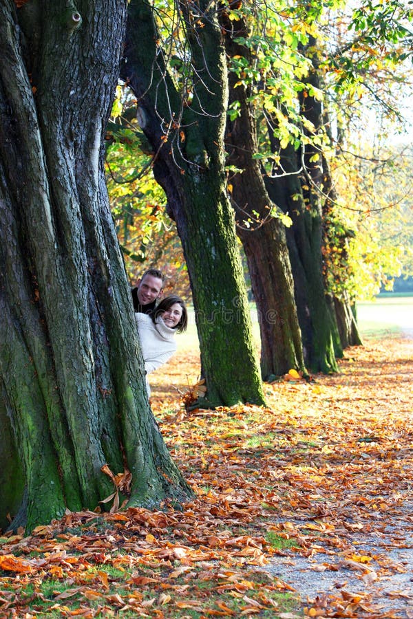 Playful Couple Peering Around an Autumn Tree Stock Image - Image of ...