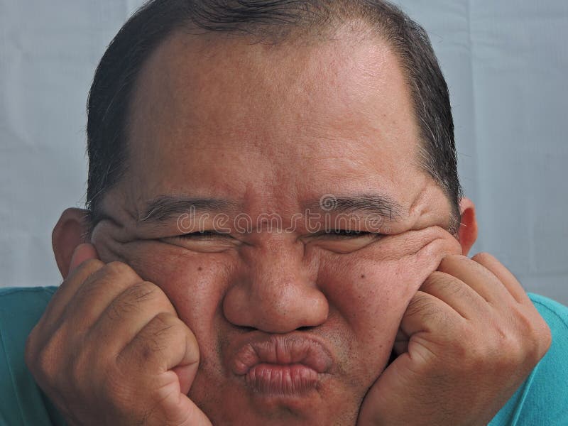 A Playful Man Making a Funny Face, Squeezing His Cheeks and Pouting ...