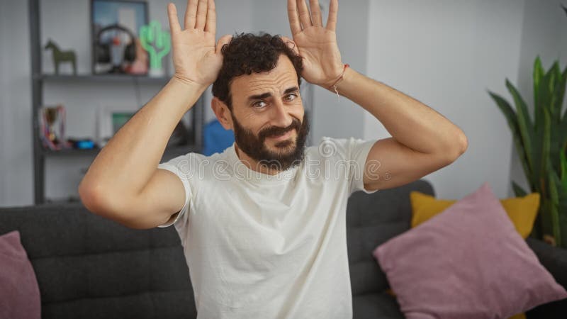 A Playful Middle-aged Man with a Beard Makes Funny Bunny Ears with His ... A Playful Middle-aged Man with a Beard Makes Funny Bunny Ears with His ...