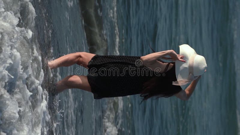 Playful Barefoot Woman Standing In Breaking Waves And Splashes On Beach