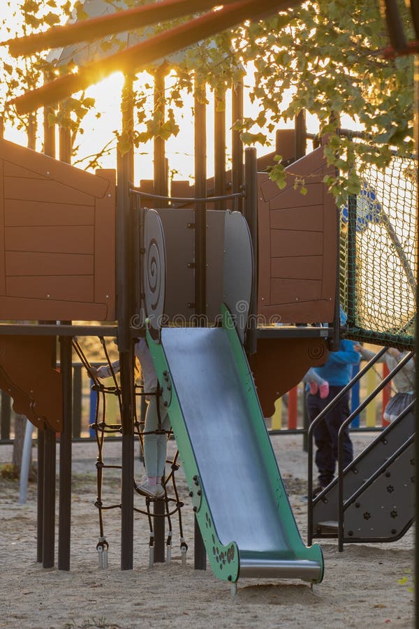 Playground at Sunset with Family and Kids Playing in the Background ...