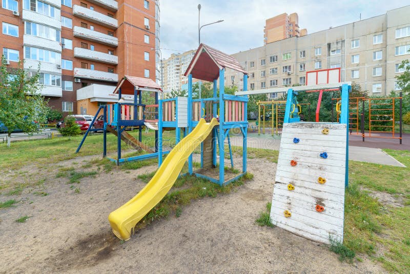 A Playground with a Yellow Slide and a White Wall with Red and Yellow ...
