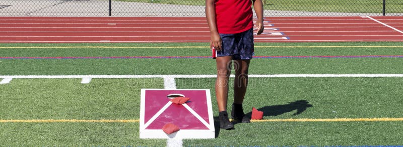 Playing Cornhole on Green Turf Standing on the Side of a Homemade Board ...
