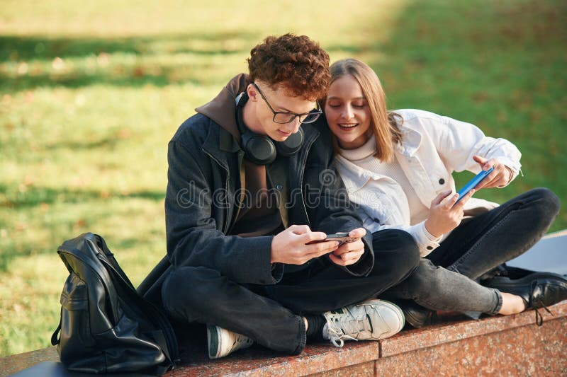 Playing Games by Using Smartphones. Two Young Students are Together ...
