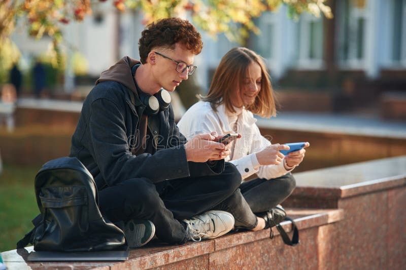 Playing Games by Using Smartphones. Two Young Students are Together ...