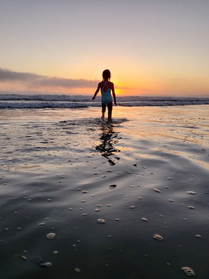 Playing in ocean at sunset stock photo. Image of child - 153079788