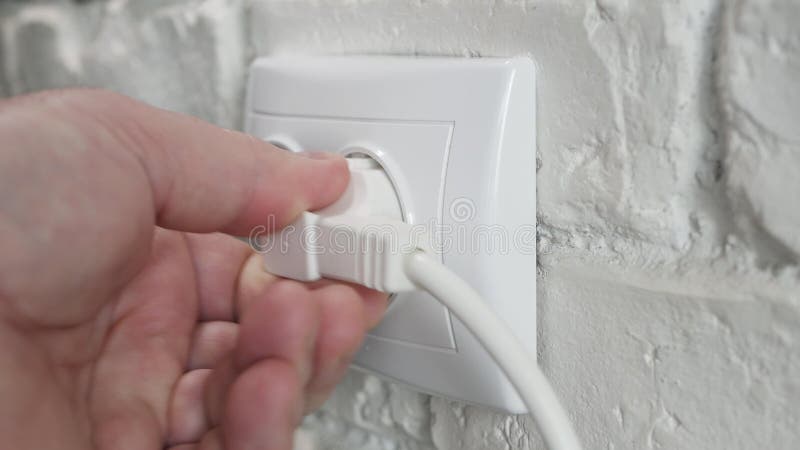 Plugging in an Electrical Power Cord with Plug To a Wall Socket in the ...