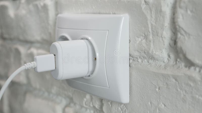Plugging a Mobile Phone Charger in an Electrical Socket on the Wall ...