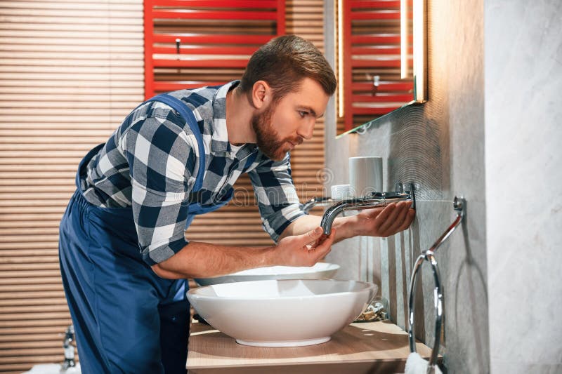 Plumber in Blue Uniform is at Work in the Bathroom Stock Photo - Image ...