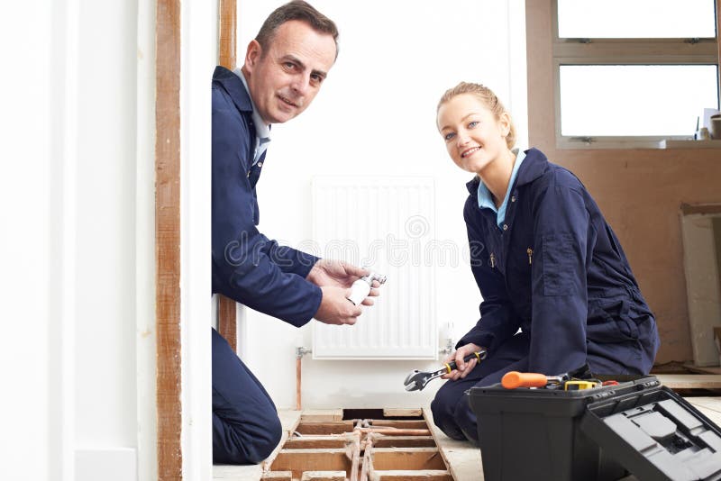 Plumber and Female Apprentice Fitting Central Heating System Stock ...