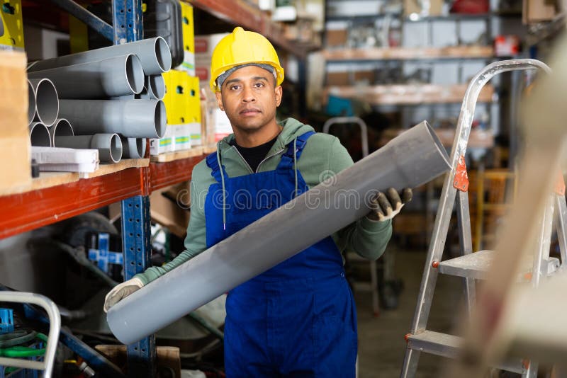 Plumber in Protective Helmet and Overalls Selects Plastic Pipes in ...
