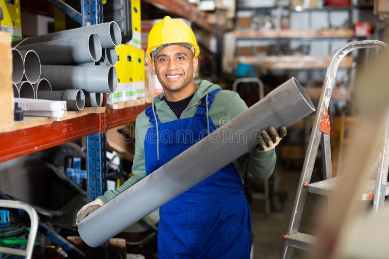 Plumber in Protective Helmet and Overalls Selects Plastic Pipes in ...