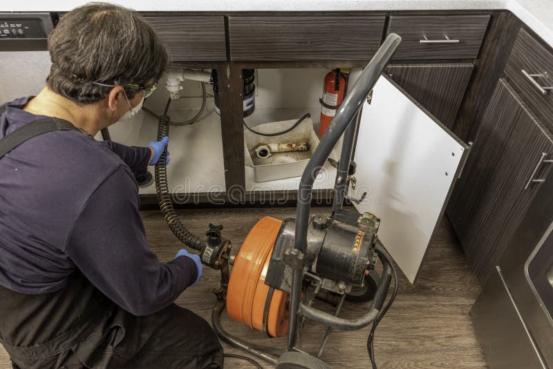 Plumber Snaking a Kitchen Sink Drain Stock Image - Image of mask ...