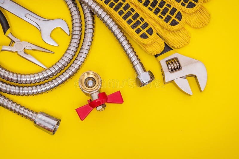 Plumbing Tools and Gloves for Connecting Water Hoses on a Yellow Table ...