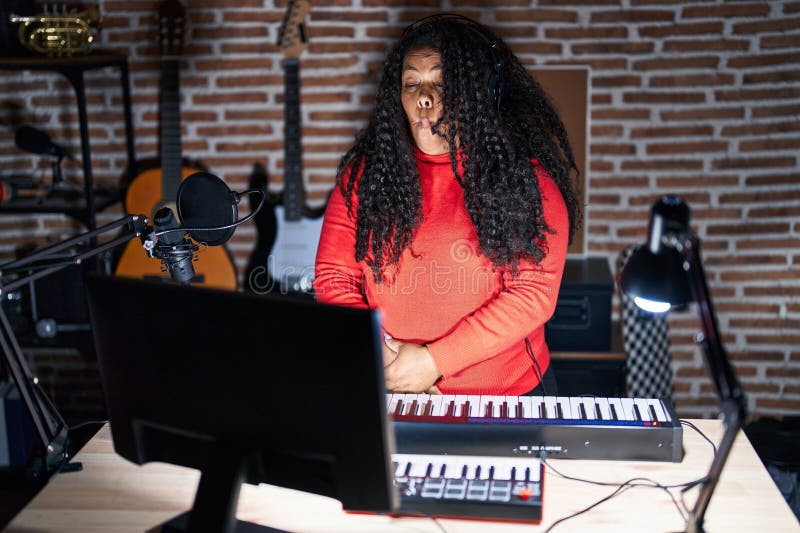 Plus Size Hispanic Woman Playing Piano at Music Studio Making Fish Face ...