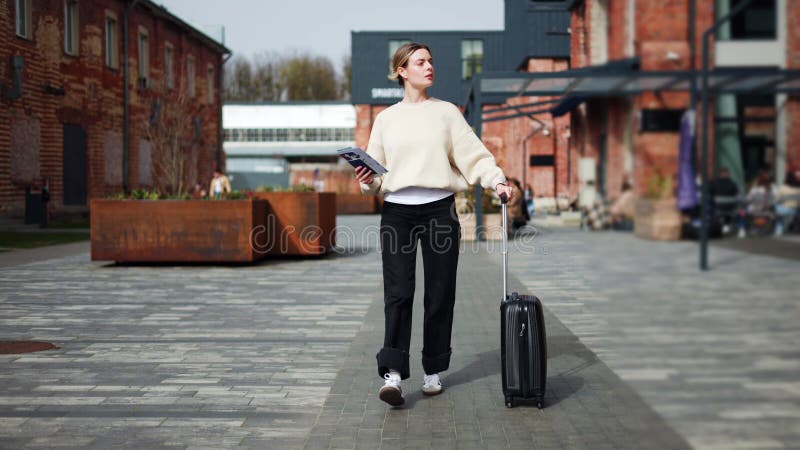 Poised Woman Striding Along Paved Path and Pulling Black Rolling ...