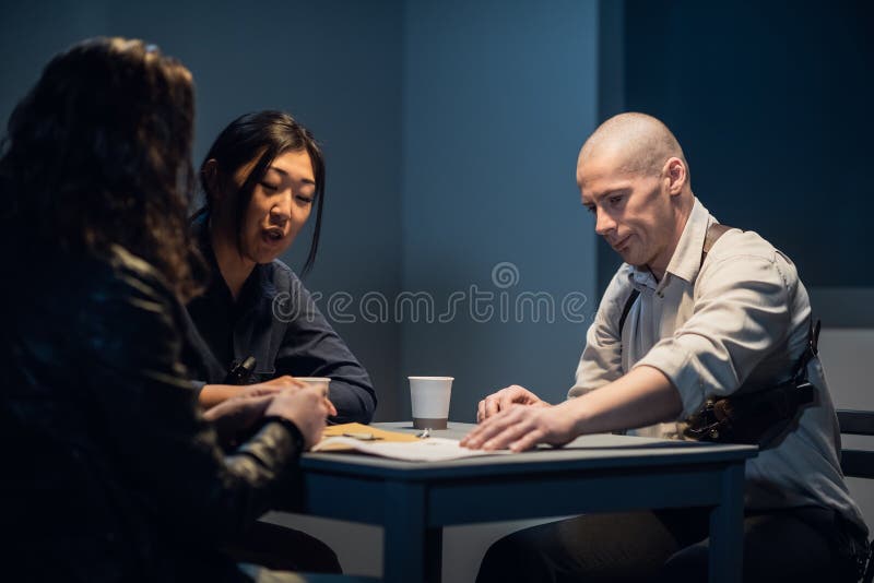At the Police Station, Two Officers are Interrogating the Captured ...