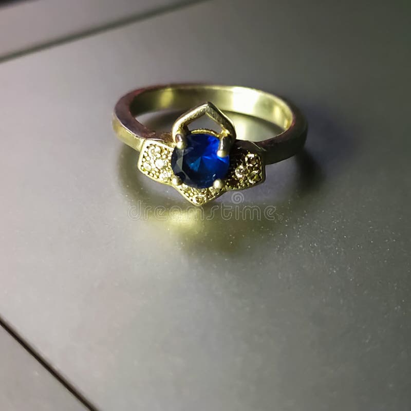 A Polished Platinum Ring with a Blue Stone on a Reflective Surface ...