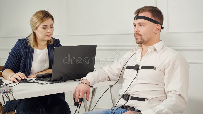 Polygraph Technician Reads Questions from a Laptop. Man Connected To ...