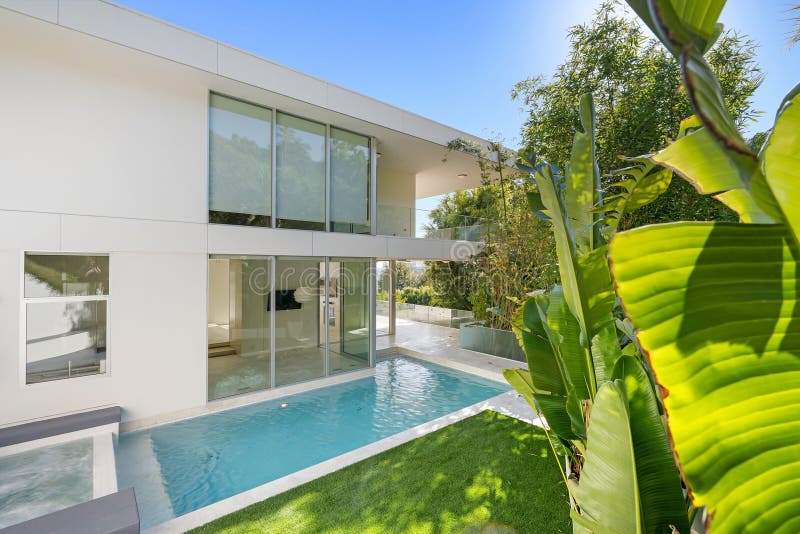 Pool Adjacent To a House with Lush Plants Alongside Stock Photo - Image ...