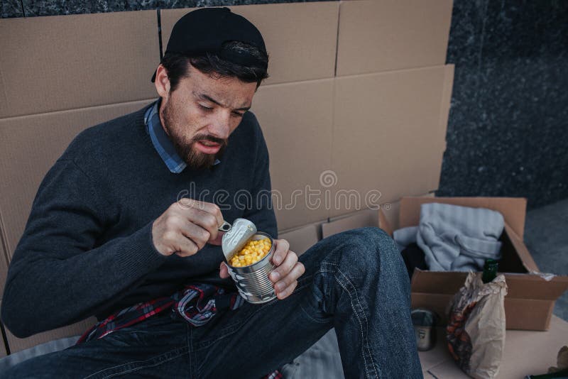 Poor and Drunk Man is Sitting on Bench and Holding a Cardboard Which ...