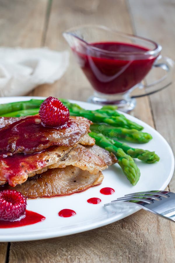 Pork Cutlets with Raspberry Sauce and Asparagus on White Plate Stock ...