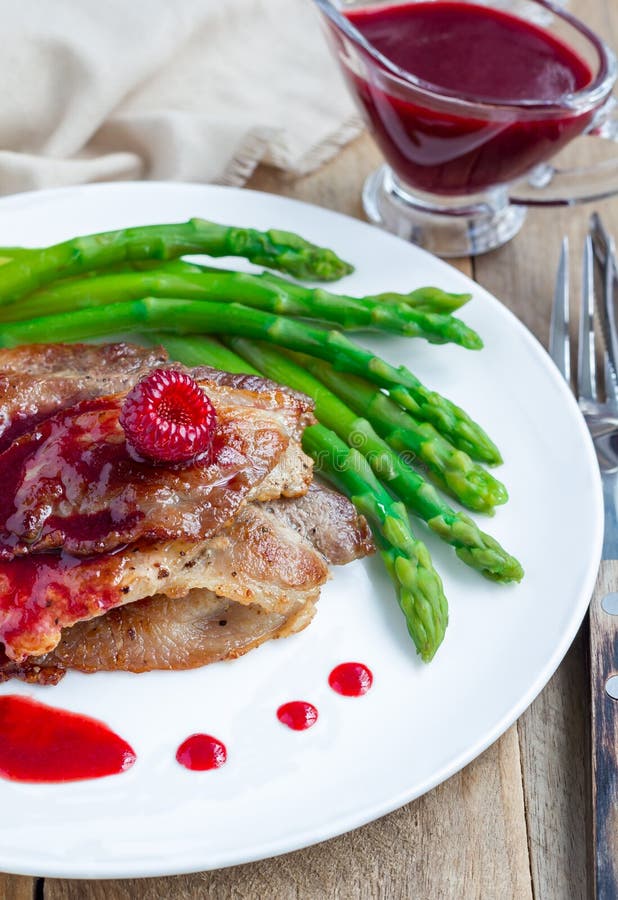 Pork Cutlets with Raspberry Sauce and Asparagus on White Plate Stock ...