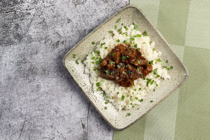 Pork Stew with Rice and Herbs on a Square Plate on a Dark Background ...