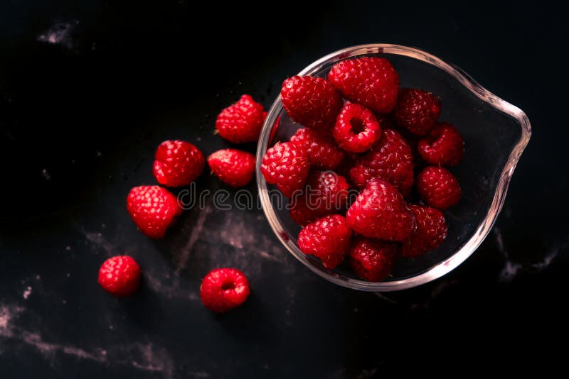 Portion of Raspberries in a Small Clear Bowl on a Black Granite Surface ...